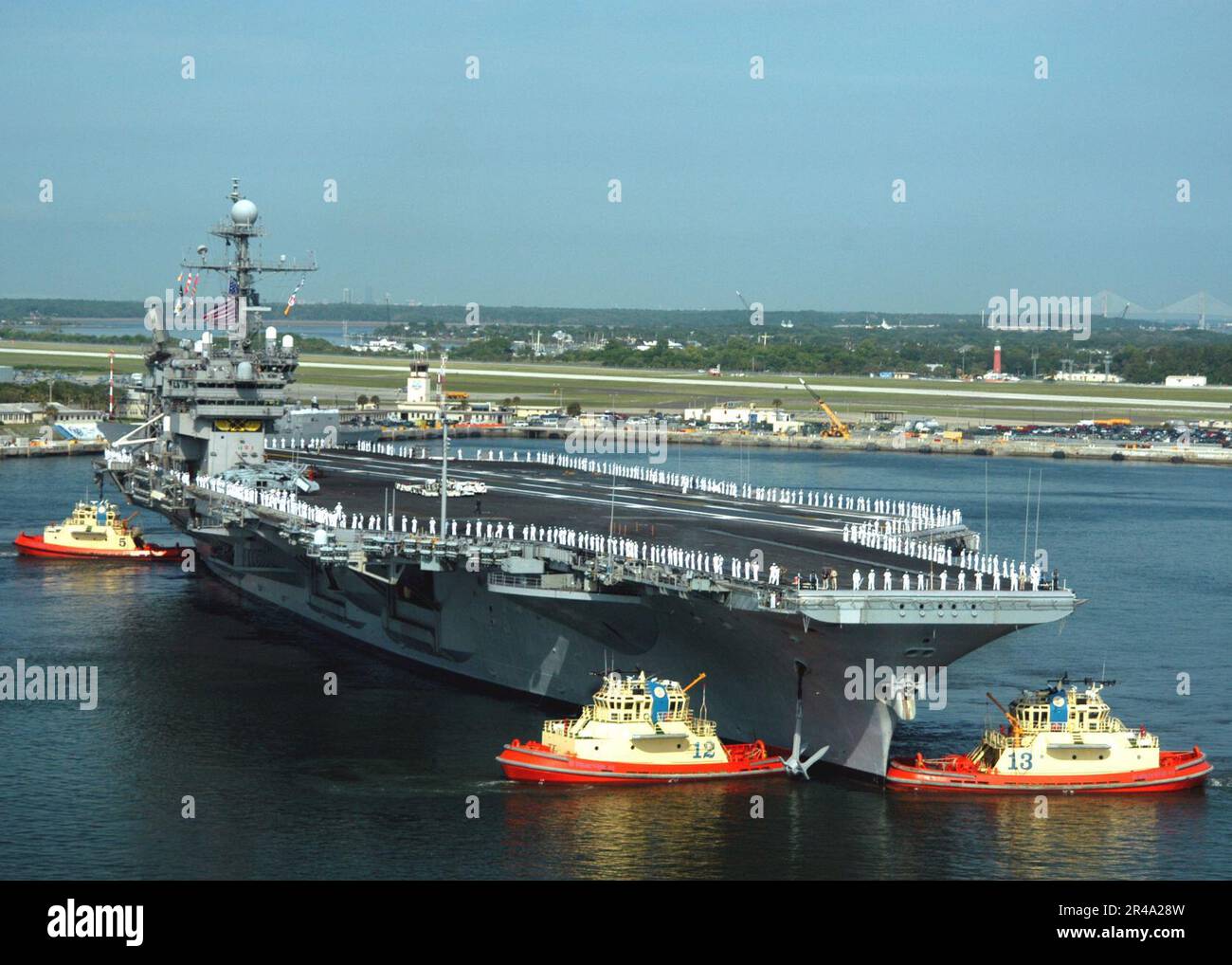 US Navy harbor tug guides the USS John F. Kennedy (CV 67) out of the ...