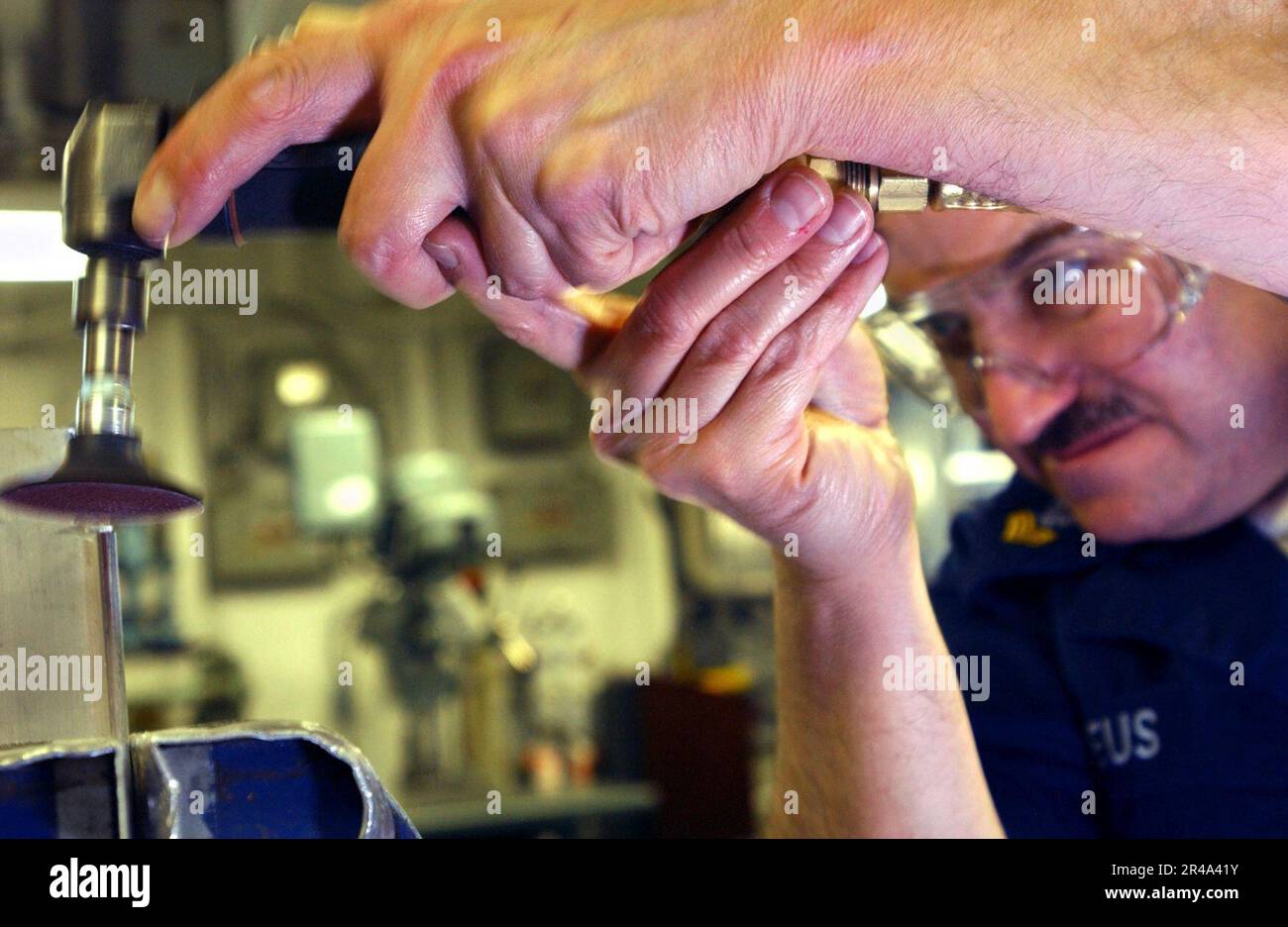 US Navy Aviation Structural Mechanic 1st Class operates a die grinder ...