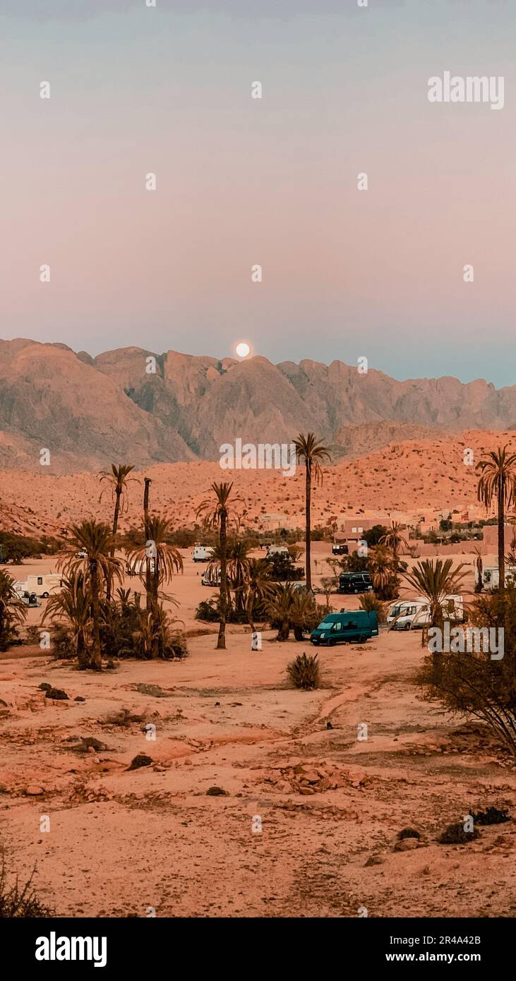 A scenic view of the full moon rising over red granite mountains, the ...