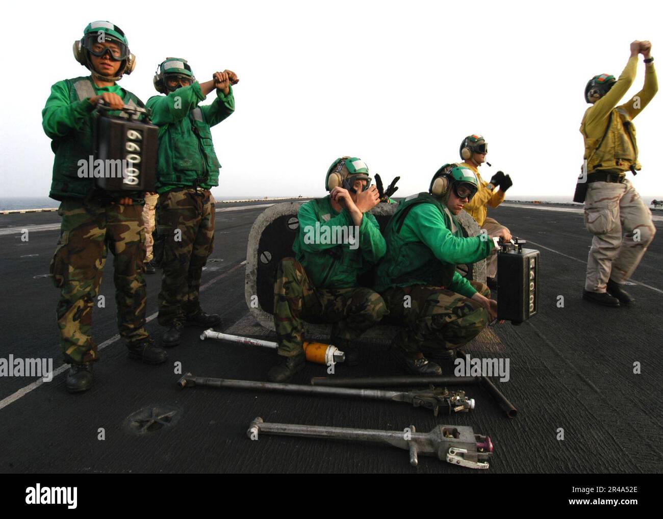 US Navy Center deck station operators signal an aircraft to stop over ...