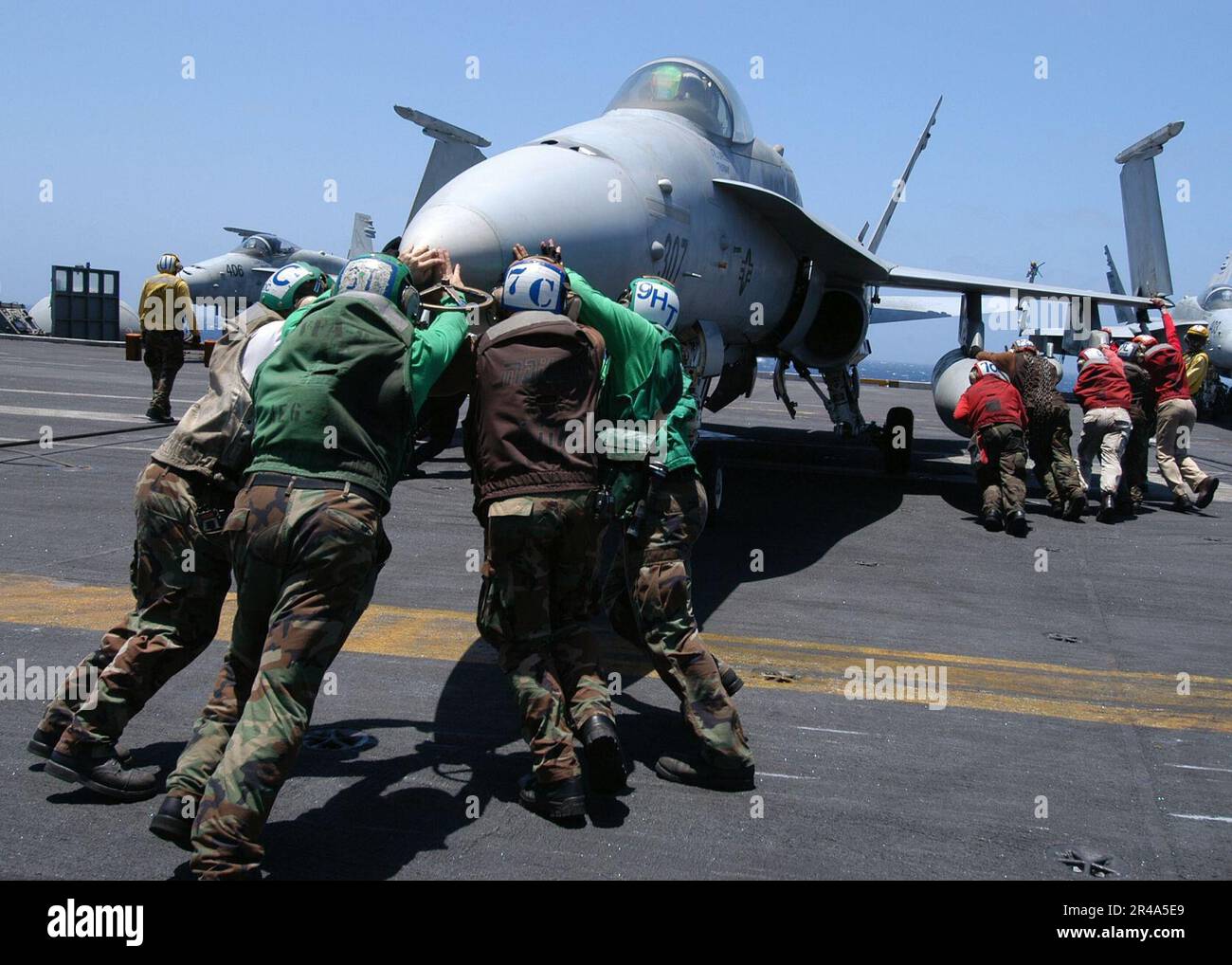 US Navy Flight deck personnel push back an F-A-18 Hornet, attached to ...
