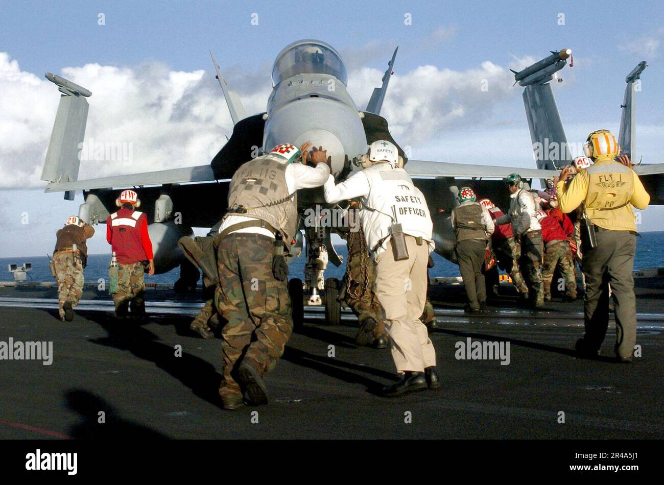 US Navy Flight deck personnel push back an F-A-18C Hornet on the flight ...