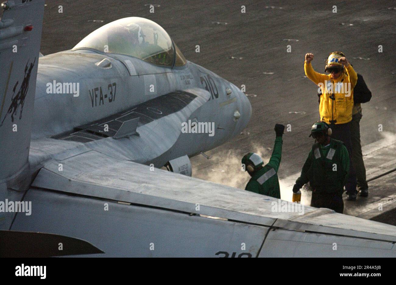 US Navy A flight deck director signals to the pilot of an F-A-18 Hornet ...