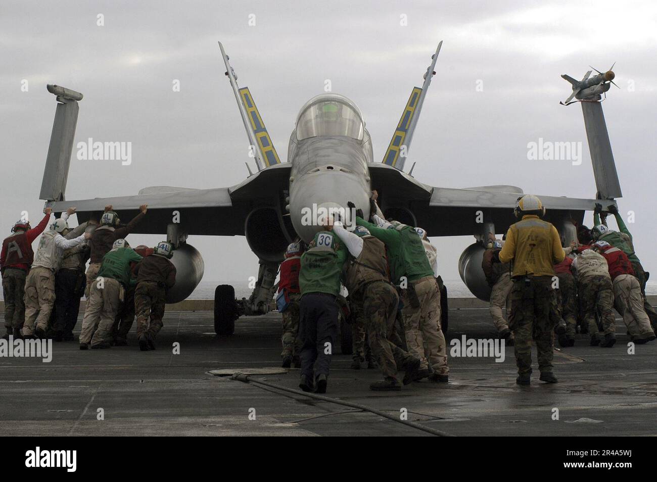 US Navy Flight deck personnel push back an F-A-18 Hornet, assigned to ...