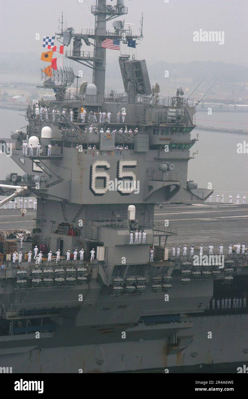 US Navy Sailors line the decks of the nuclear powered aircraft carrier ...