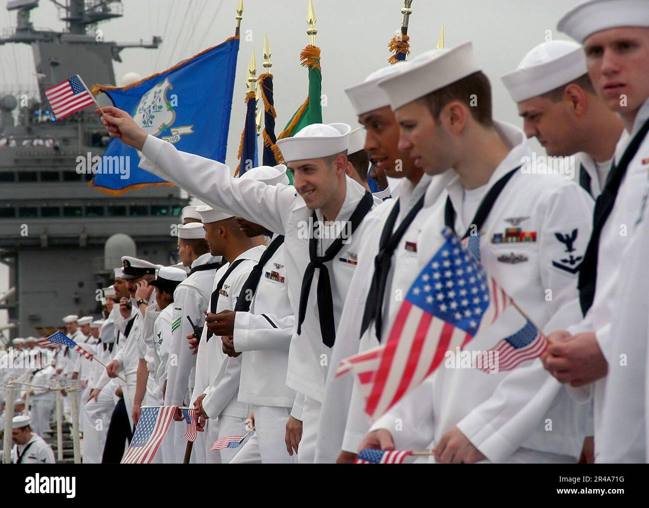 US Navy Sailors wave at family and friends waiting on the pier of Naval ...