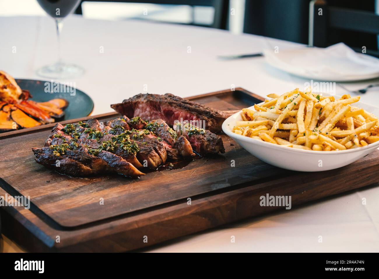 The medium rare bone in ribeye steak with a side of truffle fries on a ...