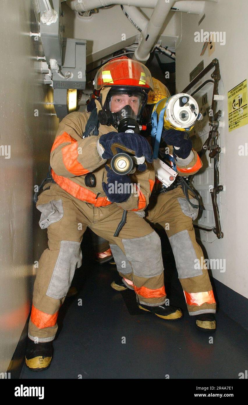 US Navy Damage Controlmen participating in a fire drill, use a Naval ...
