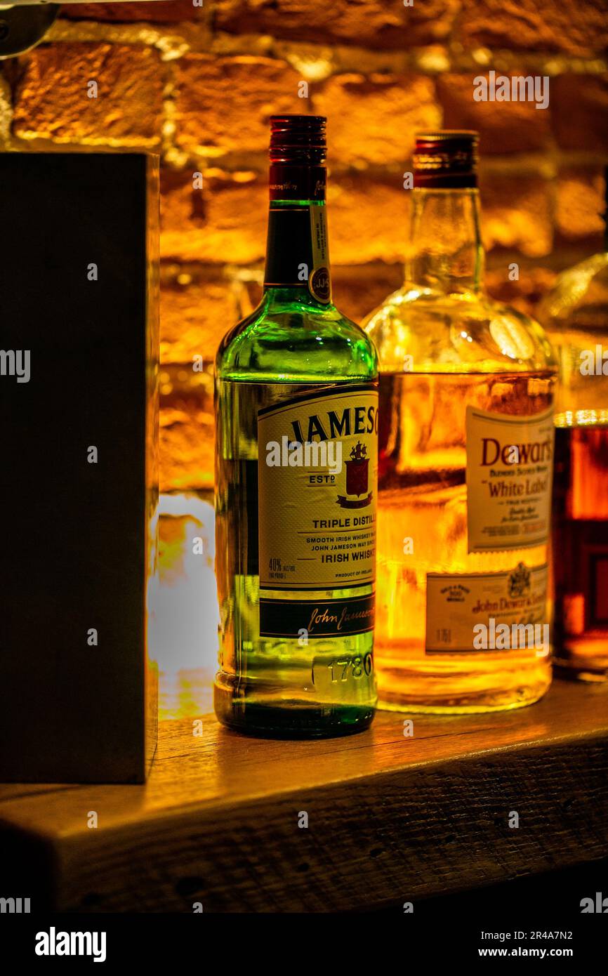 A close-up of a shelf of various types of alcoholic beverage bottles ...