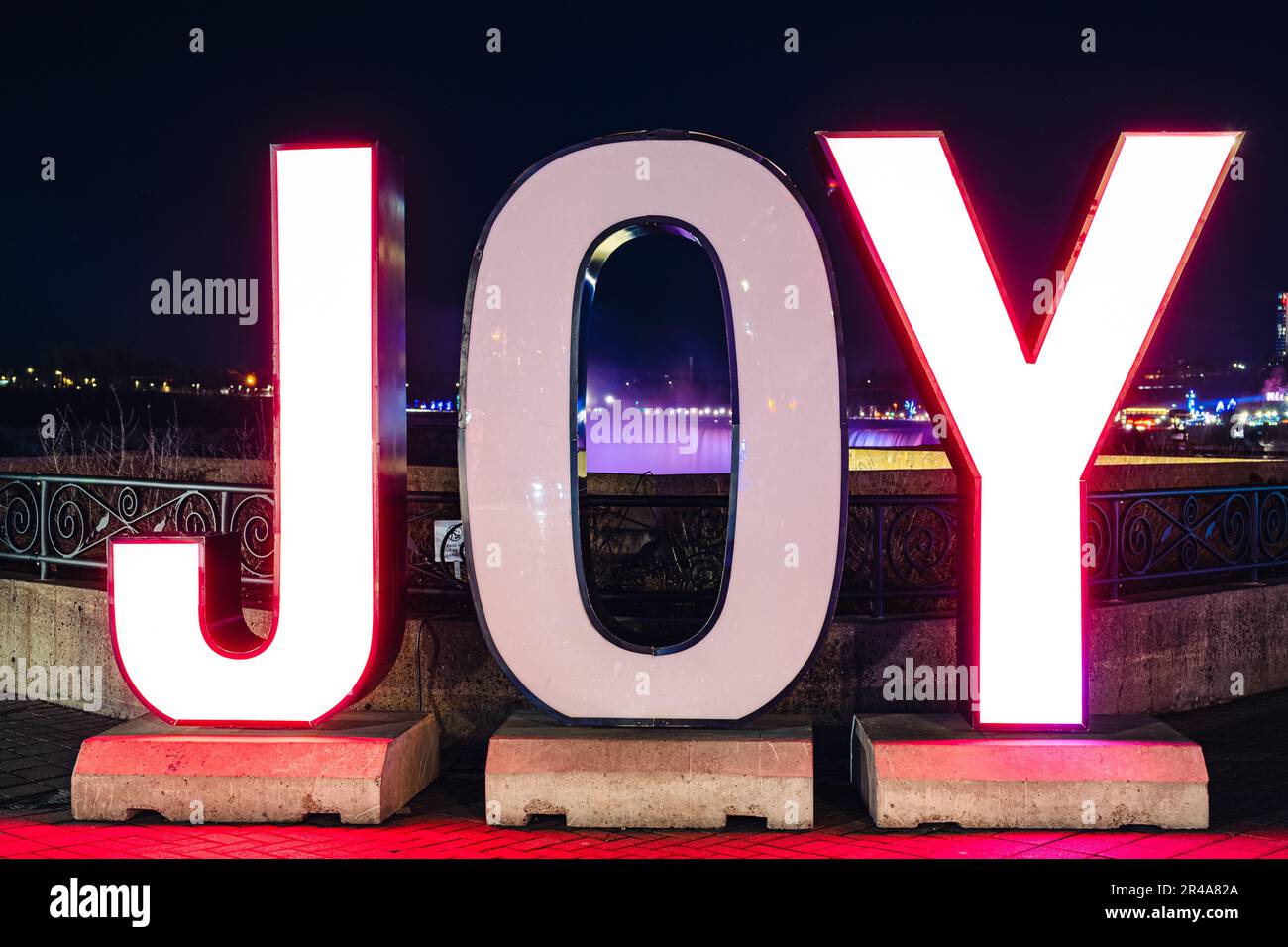 A vibrant, illuminated red and white sign of the word 'Joy' set against ...