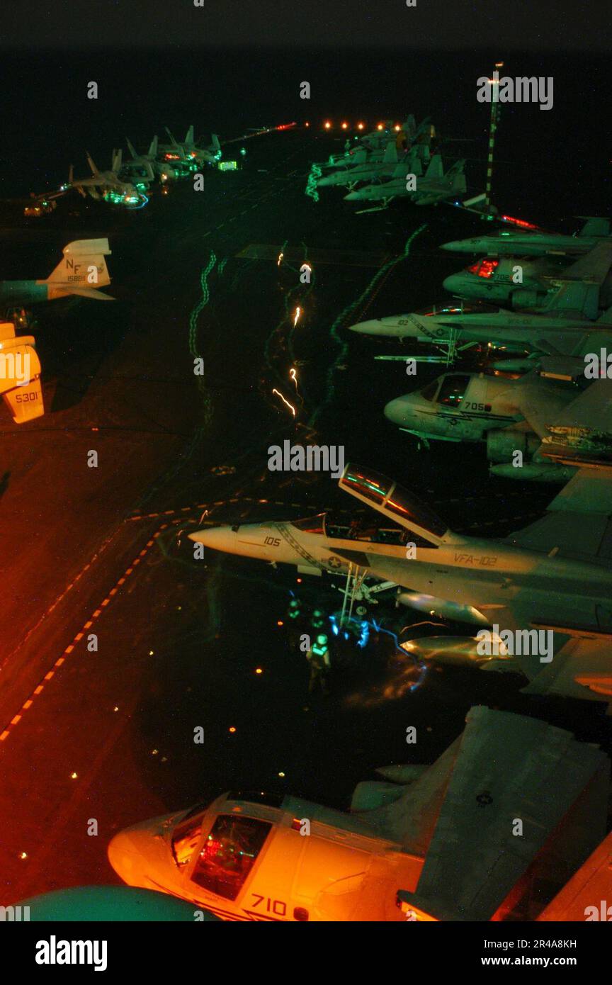 US Navy Personnel move about the flight deck during night operations ...