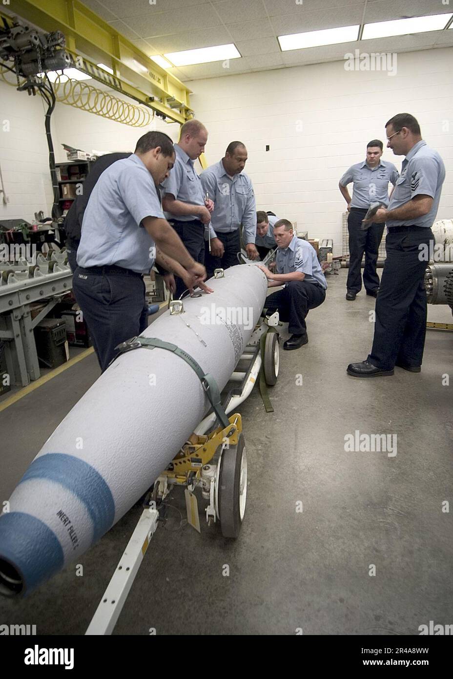 US Navy Students practice working with an inert practice bomb during a ...
