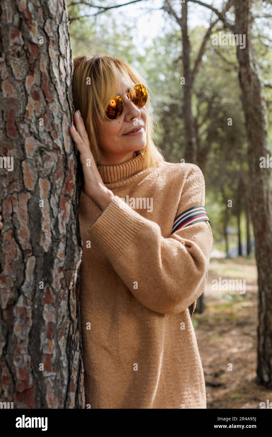An attractive mature woman standing in an outdoor setting surrounded by ...
