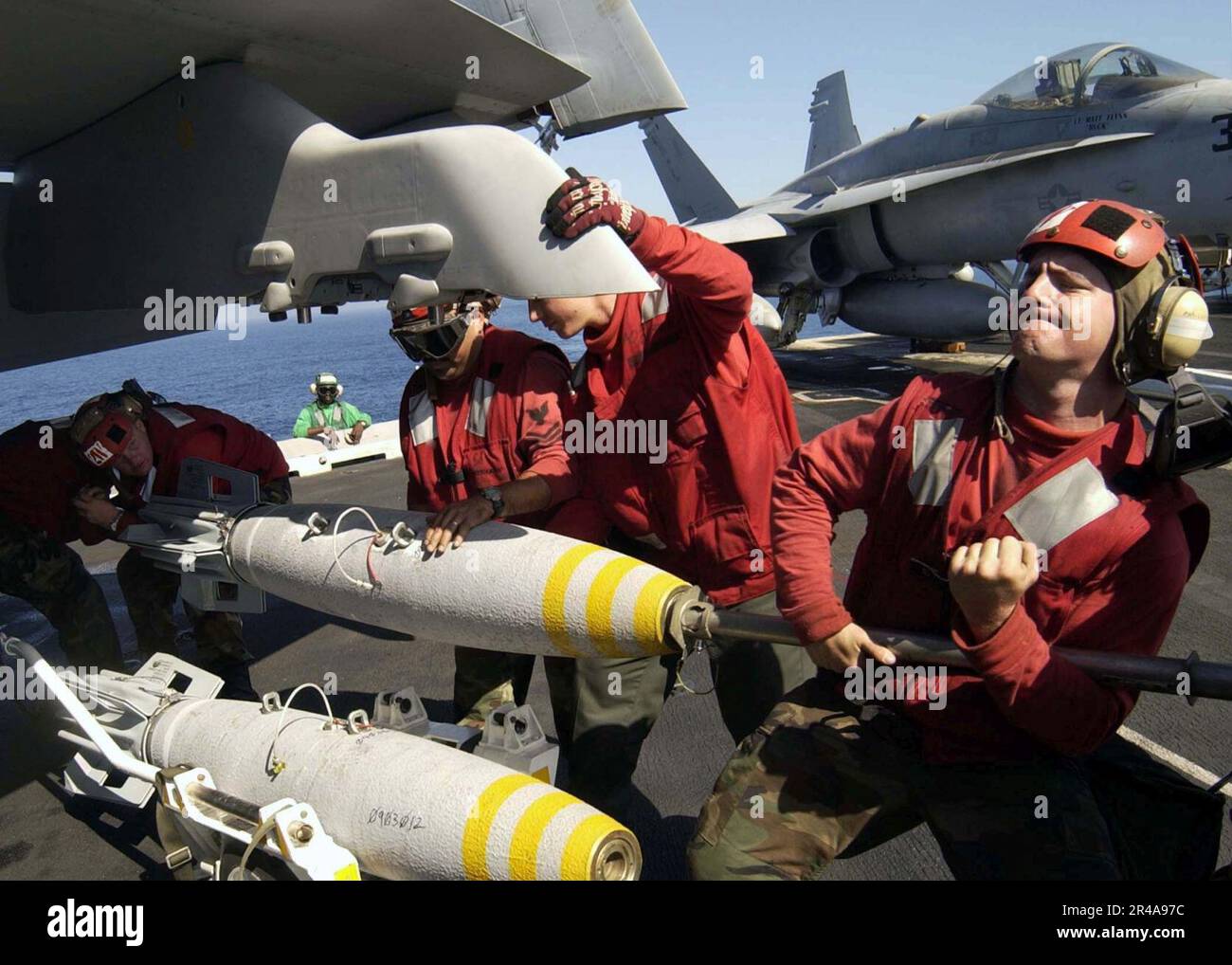 US Navy Aviation Ordnancemen load a 500lb. Mk-82 general purpose bomb on an F-A-18E Super Hornet ...