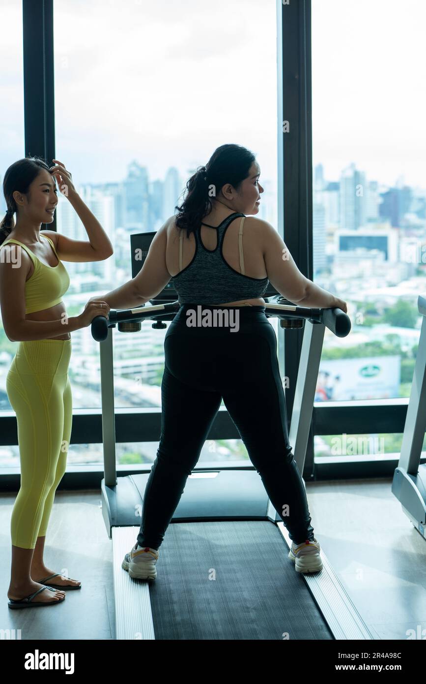 Fitness instructor trains fat woman stretching Yoga meditates against ...