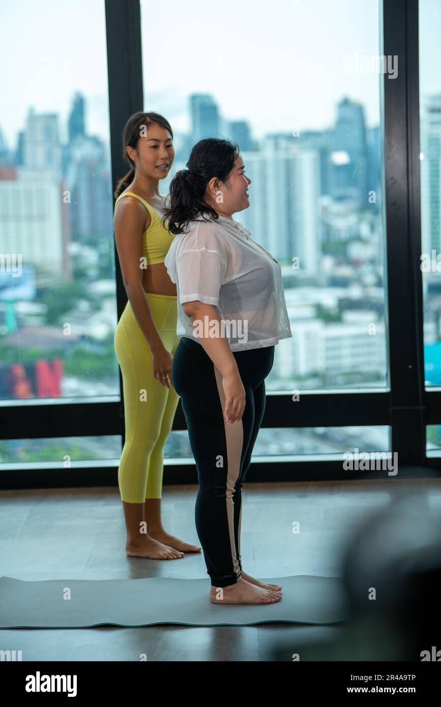 Fitness instructor trains fat woman stretching Yoga meditates against ...