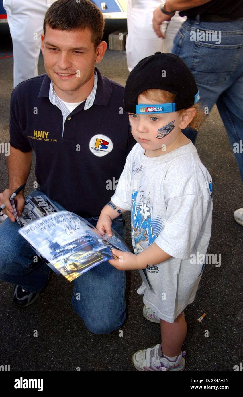 US Navy NASCAR driver Casey Atwood signs a picture for a young race fan ...