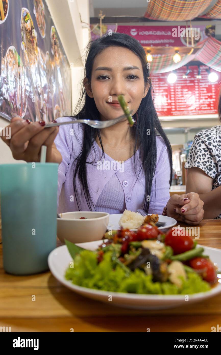 A young woman eating a yard long bean salad in a Thai restaurant Stock ...