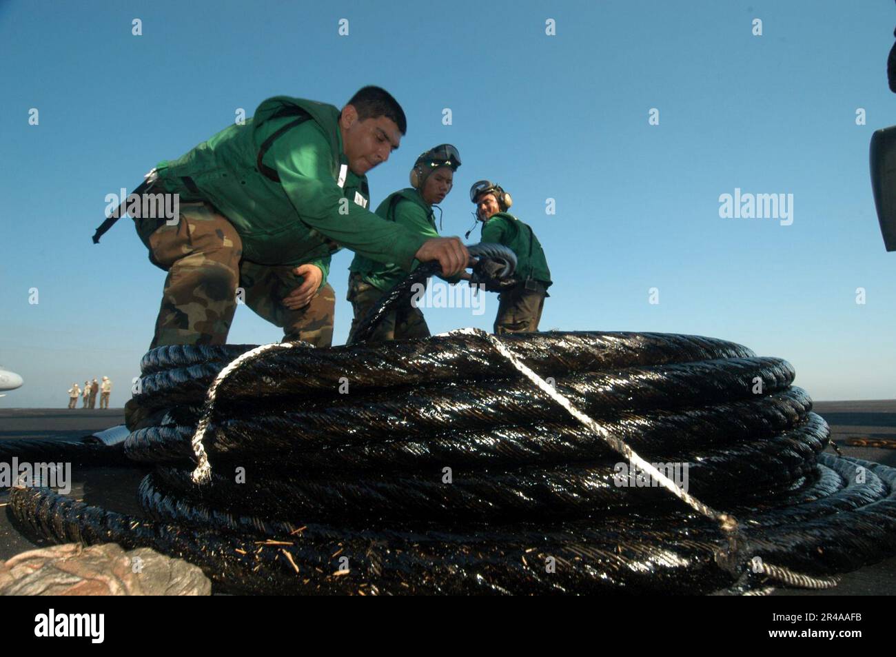 US Navy Sailors assigned to V-2 Division, unravel an arresting gear ...