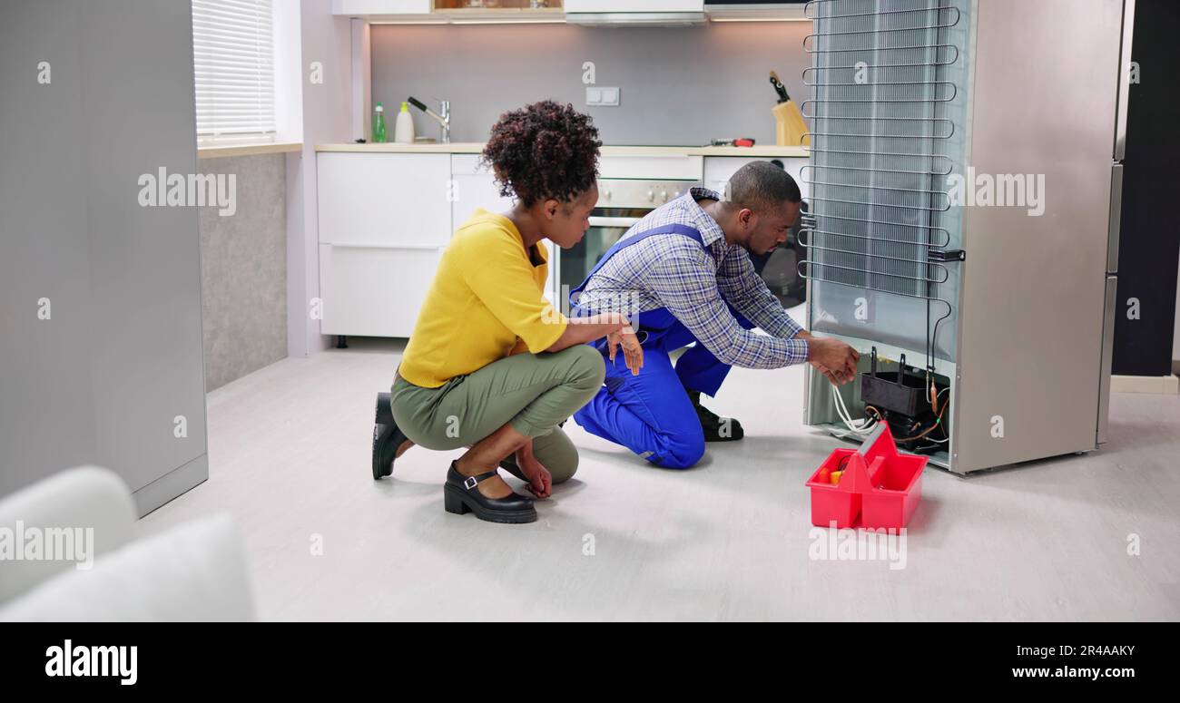 Broken Fridge Repair By African American Worker Stock Photo - Alamy