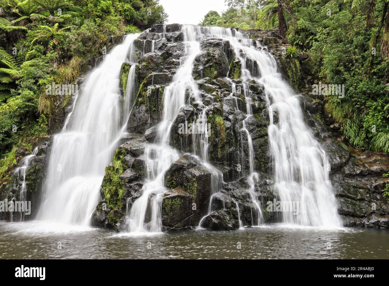 A majestic waterfall cascading down a lush green forest landscape in ...