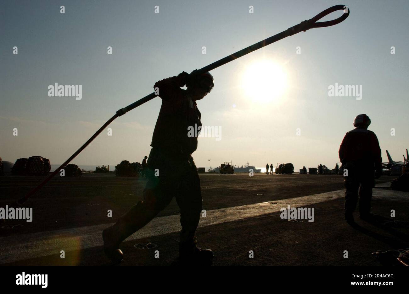 US Navy An Aviation Ordnanceman carries a cargo sling across the flight ...