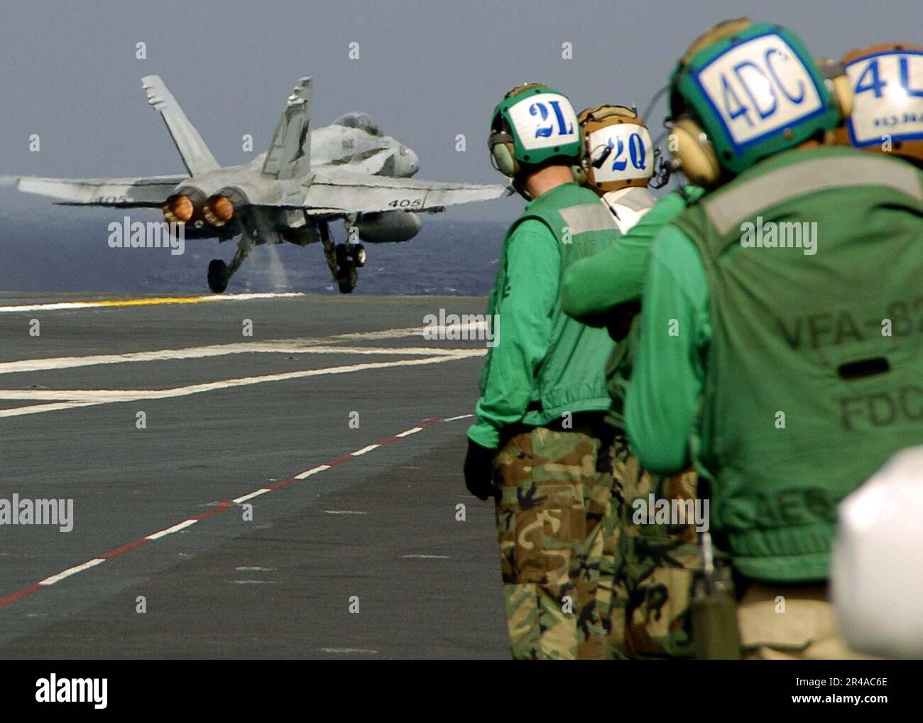 US Navy Flight deck personnel observe as an F-A-18C Hornet assigned to ...