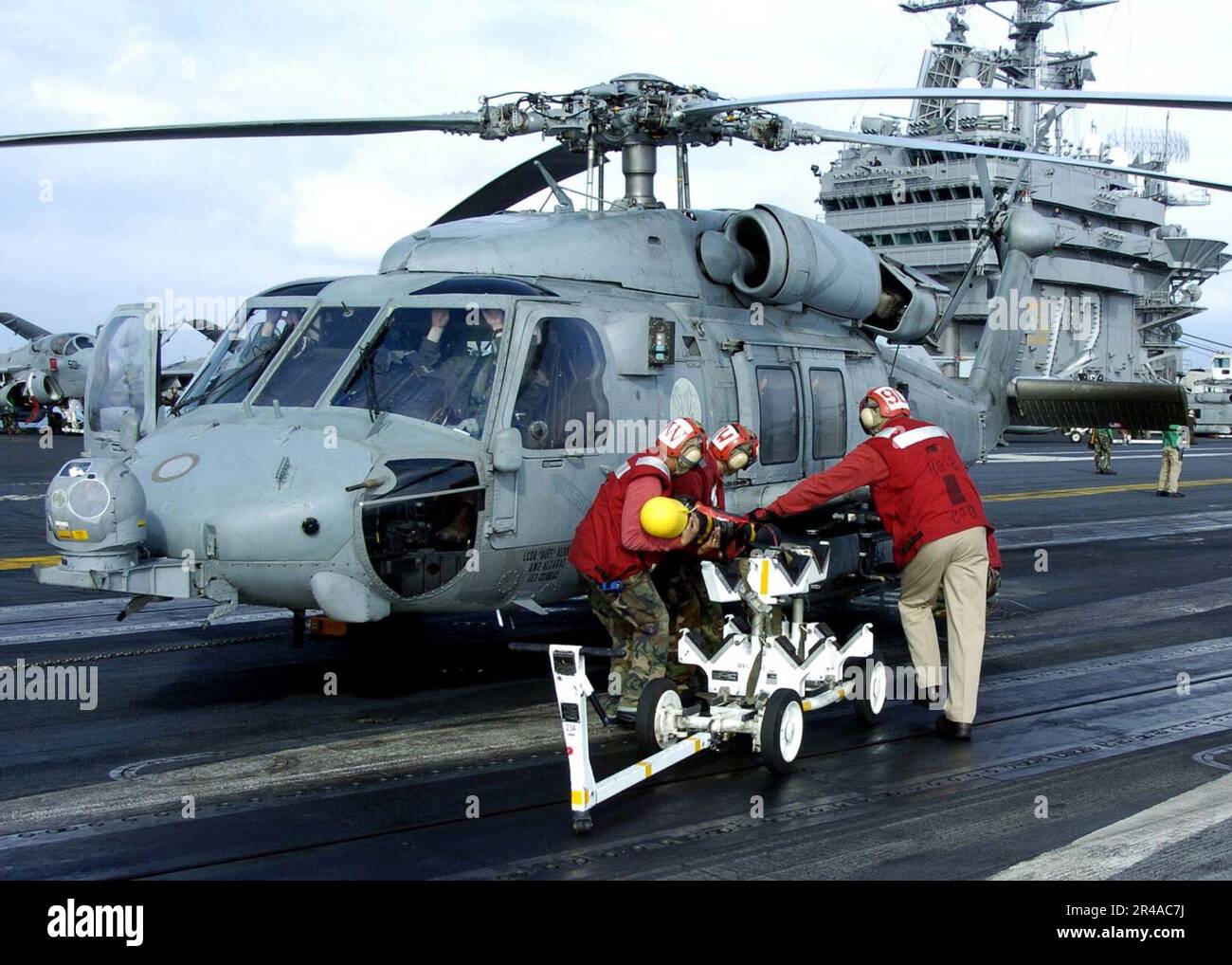 US Navy Aviation Ordnancemen load a AGM-114 Hellfire missile onto an HH ...