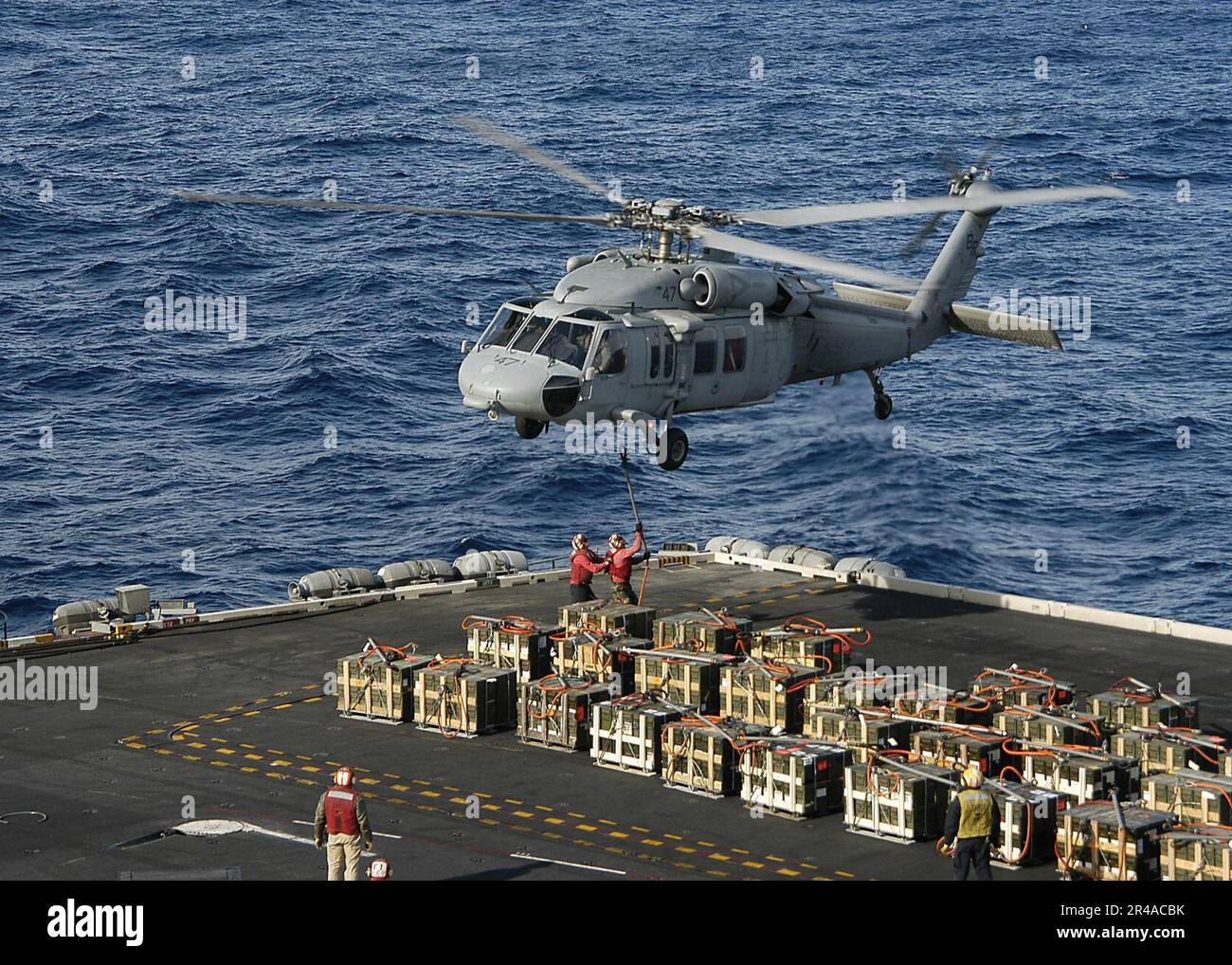 US Navy Weapons Department personnel connect a cargo pendant to an MH ...