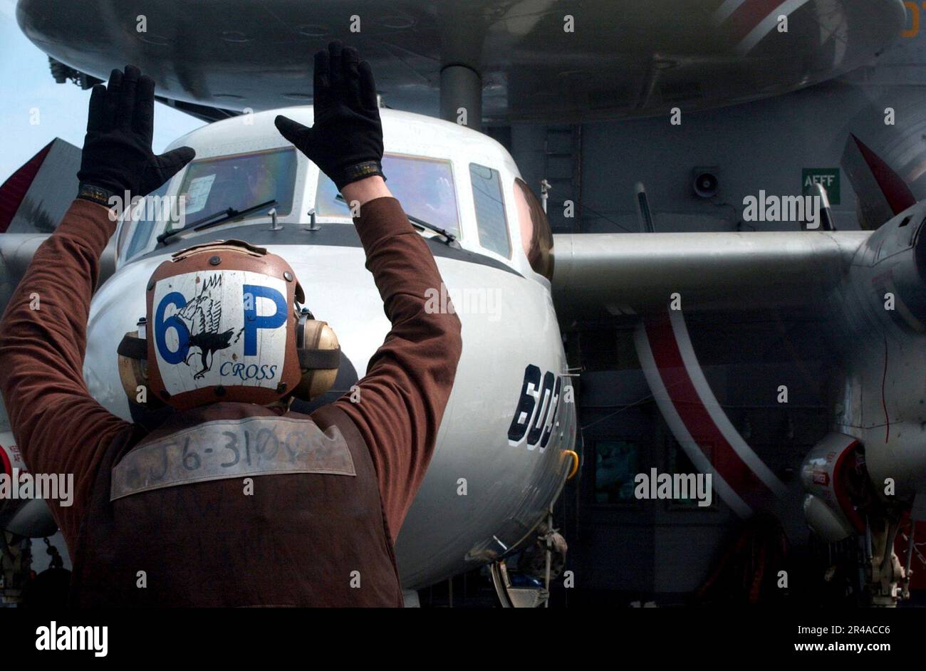 US Navy A plane captain uses hand signals to communicate with the air ...