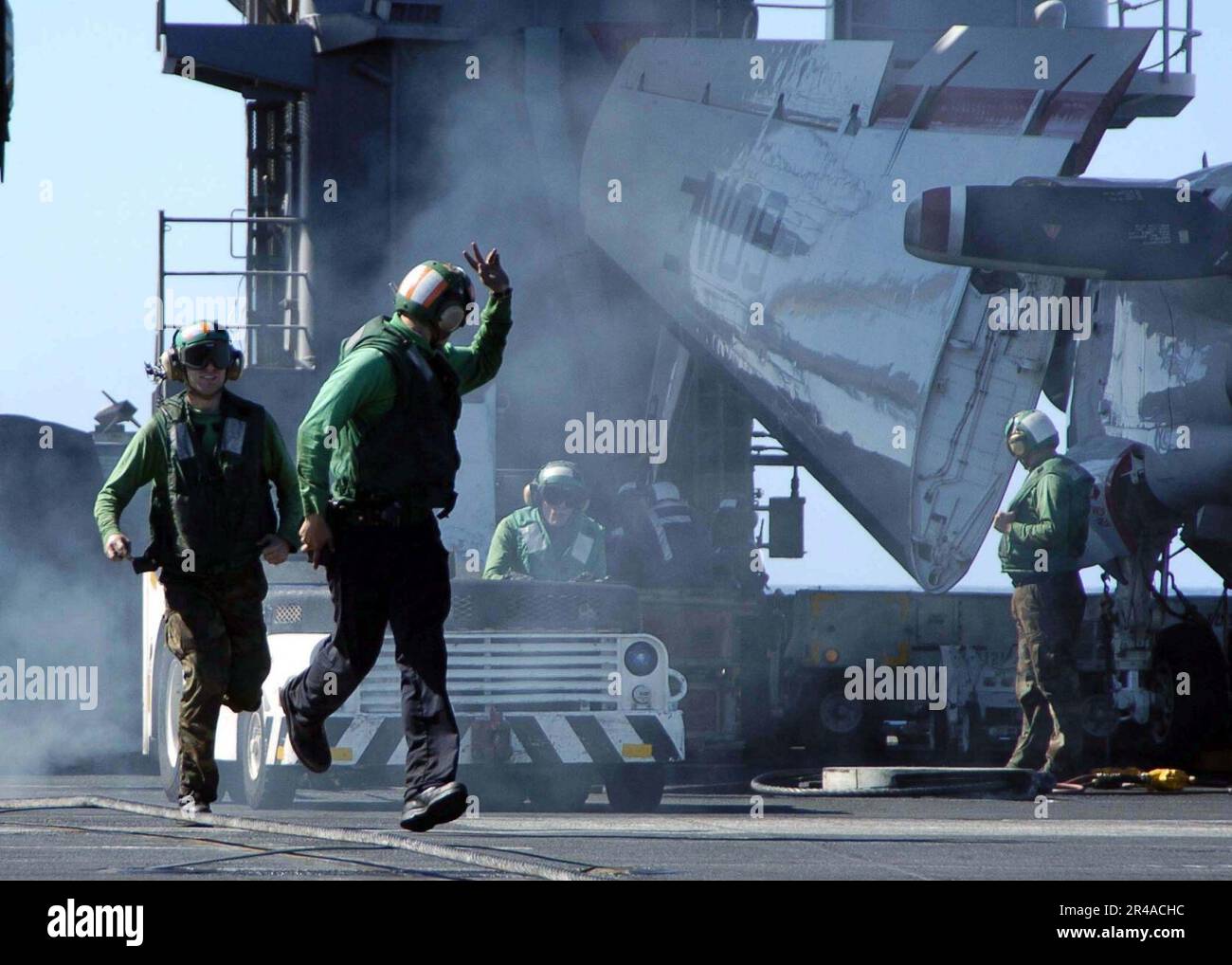 US Navy Flight deck personnel guide a tractor used to help rig a ...
