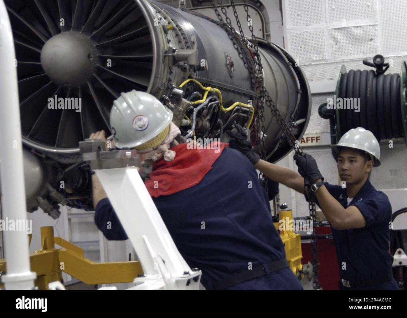 US Navy Sailors perform maintenance on an F-A-18 Hornet engine in the ...