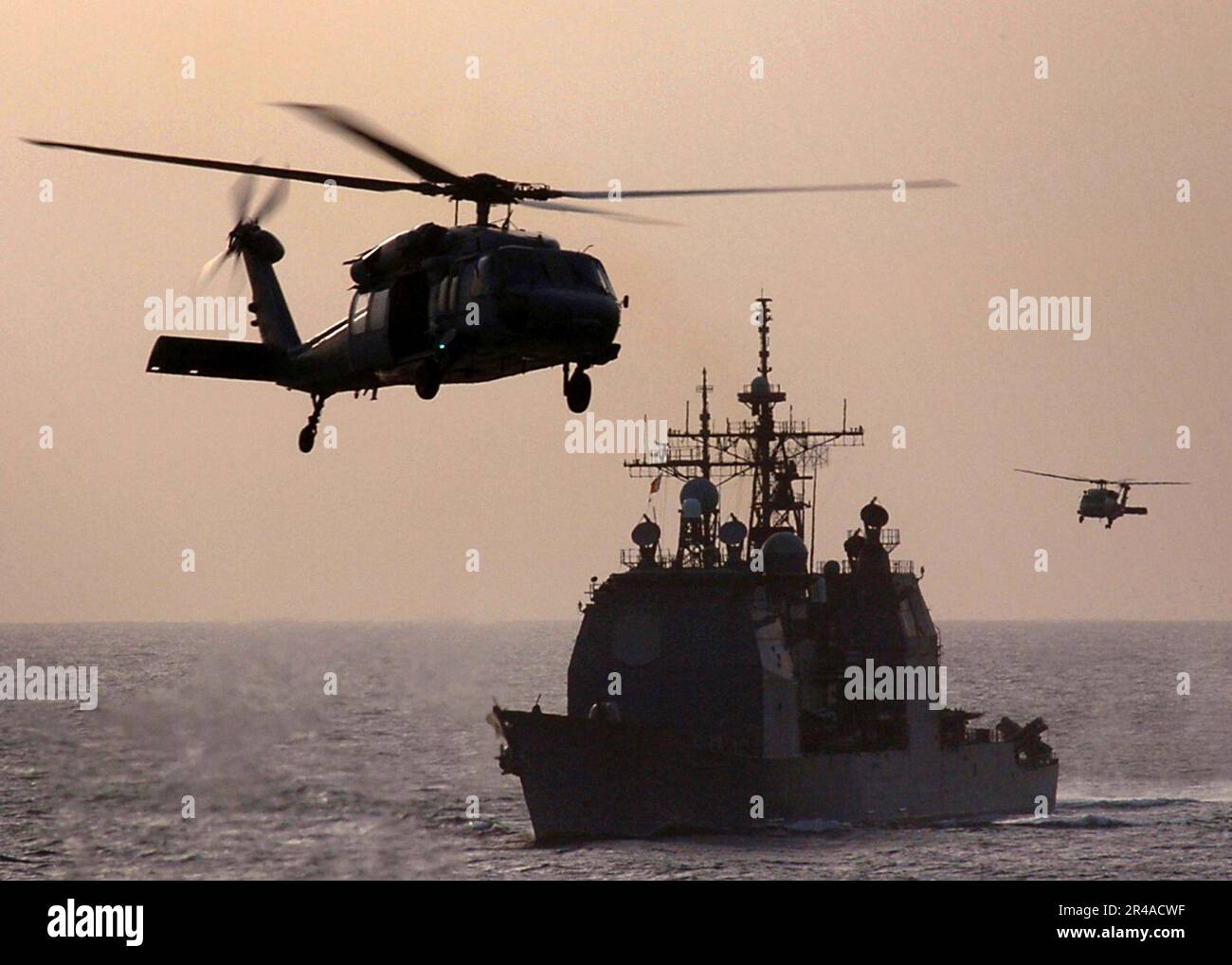 US Navy An MH-60S Knighthawk helicopter crosses the bow of the guided ...