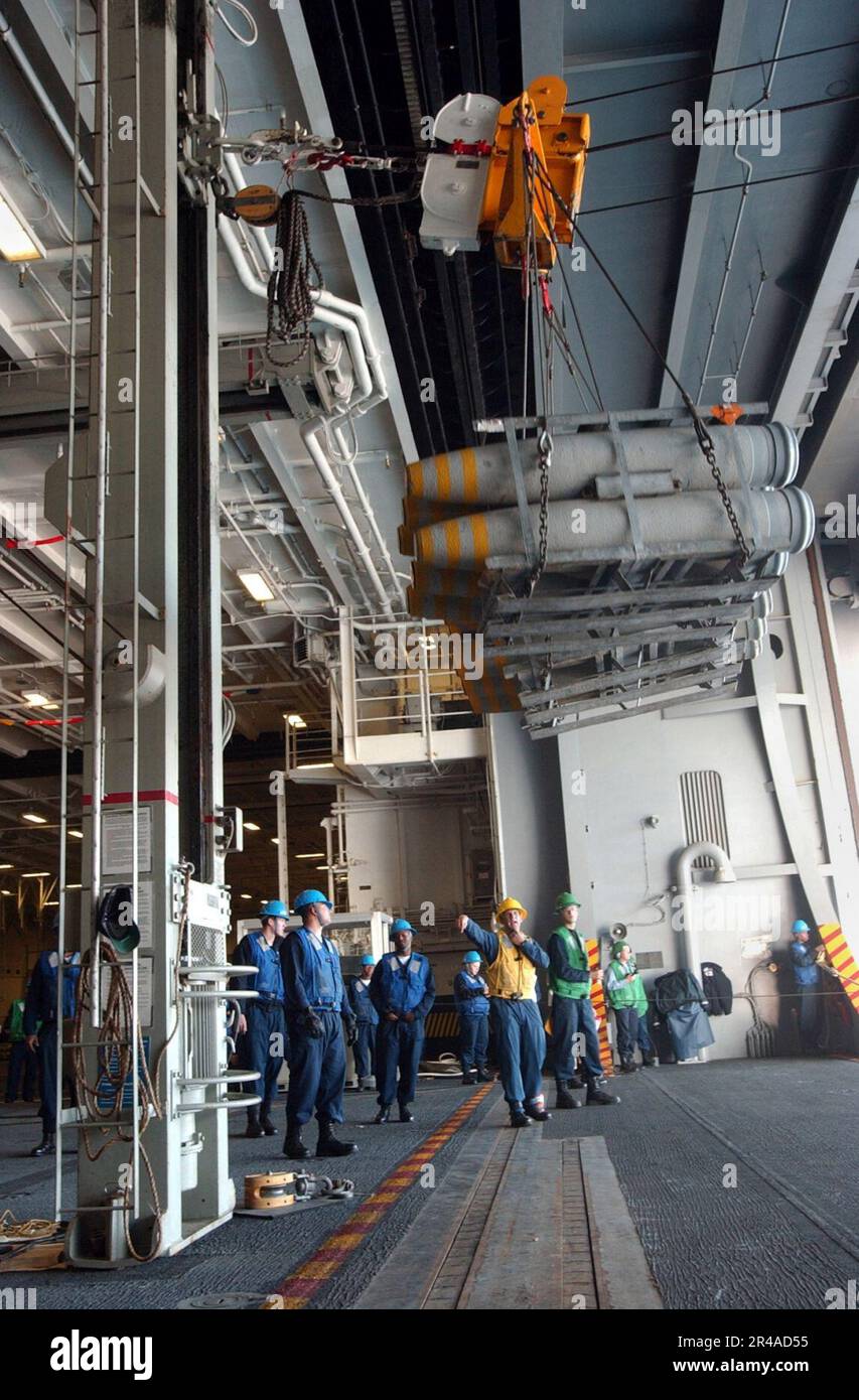 US Navy Boatswain's Mate 1st Class center, gives a hand signal to the ...