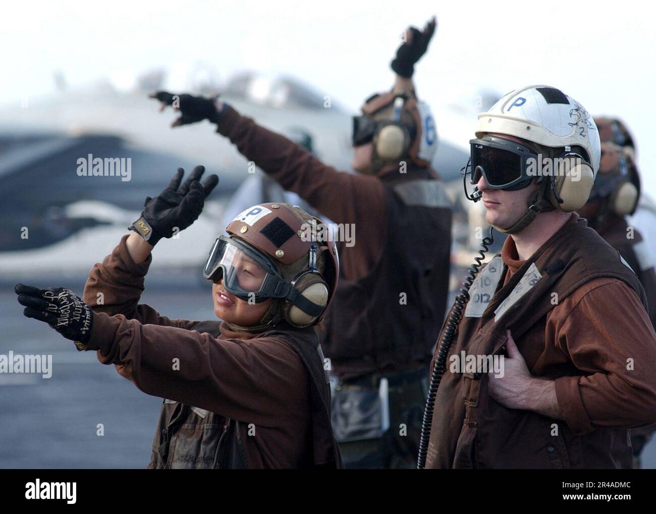 US Navy Aviation Machinist's Mate 3rd Class (left) signals a pilot to ...
