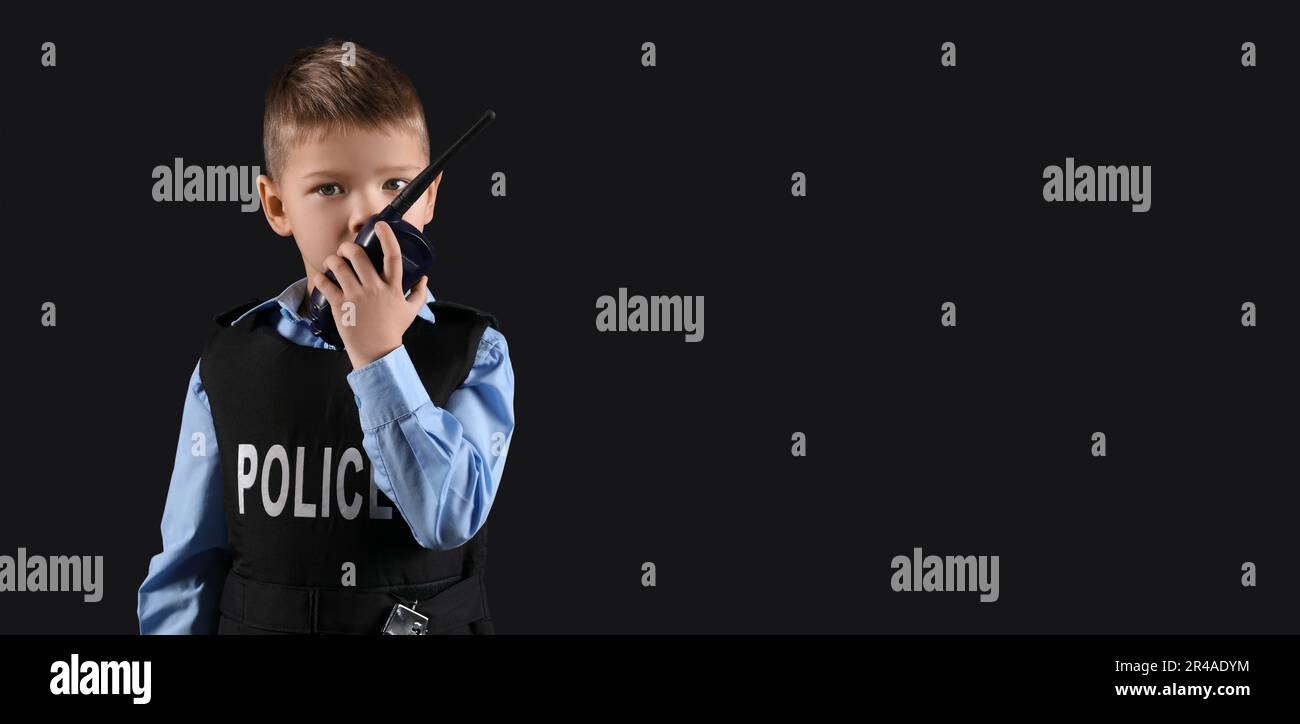 Cute little police officer with radio transmitter on black background ...
