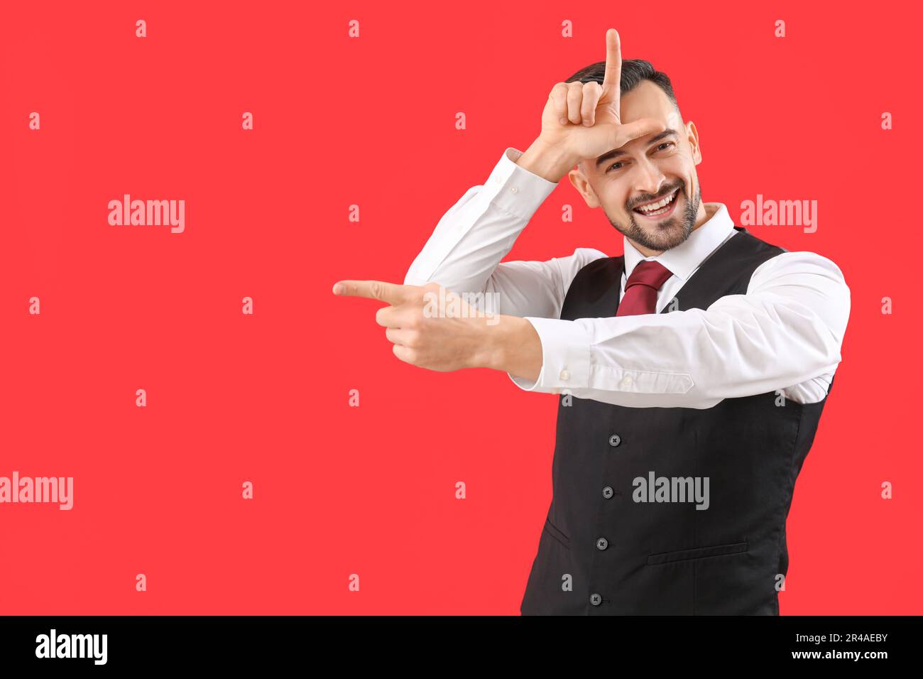 Handsome man showing loser gesture on red background Stock Photo - Alamy