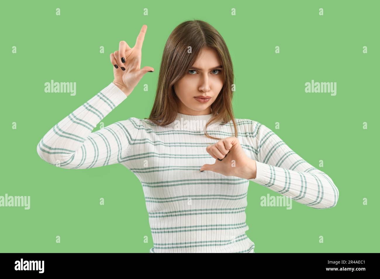 Sad young woman showing loser gesture on green background Stock Photo ...