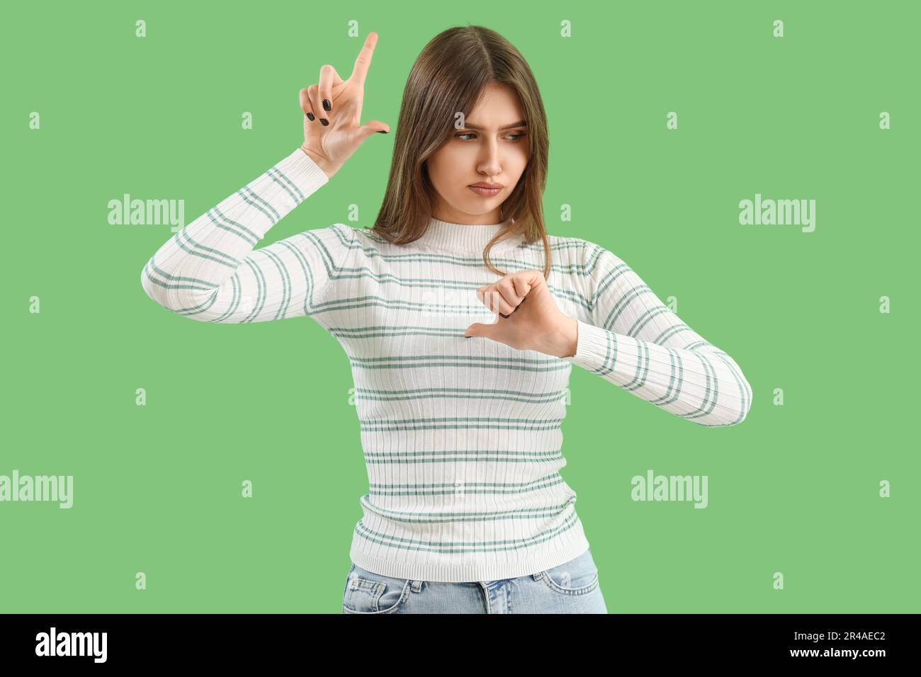 Sad young woman showing loser gesture on green background Stock Photo ...