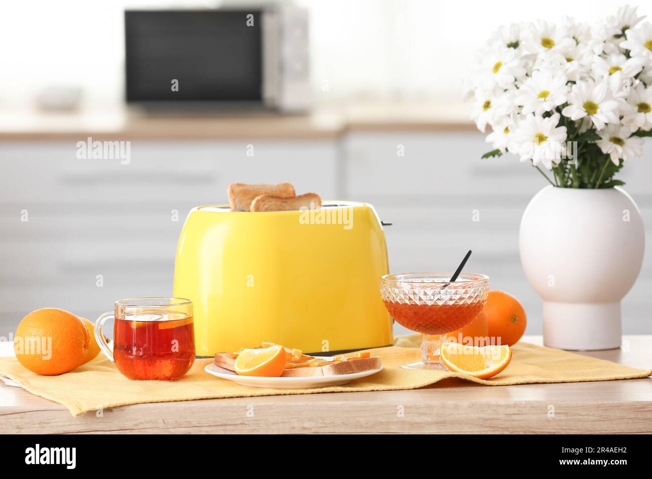 Toaster with bread slices, orange jam toasts and cup of tea on table in ...