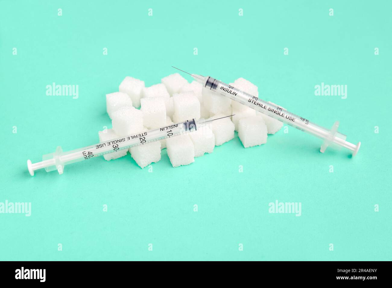 Sugar cubes with syringes for insulin injection on green background ...