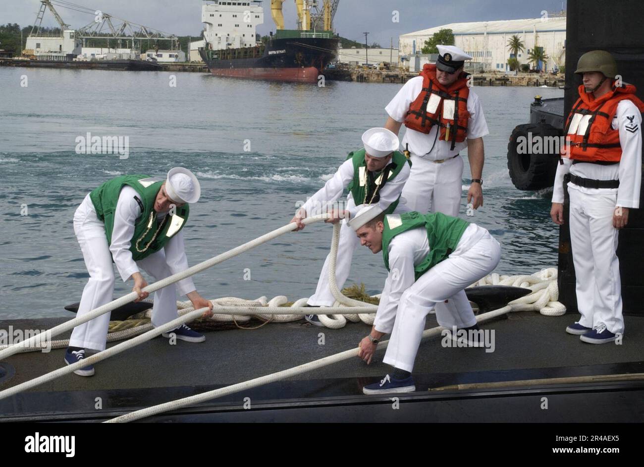 US Navy Crew members haul in the mooring lines aboard the nuclear ...