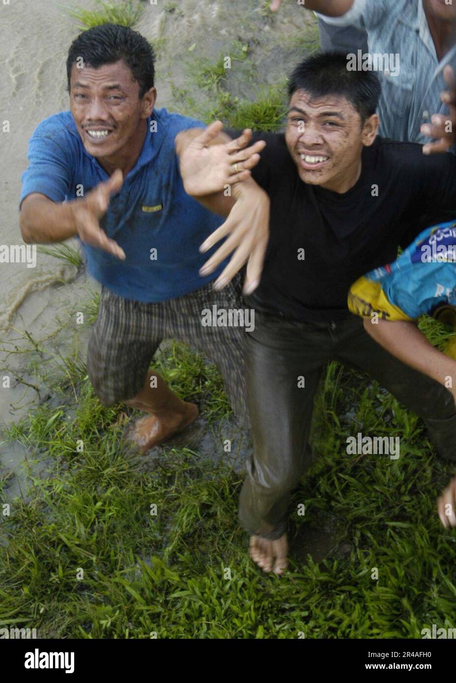US Navy Two Indonesian men from a small village reach to catch food and ...