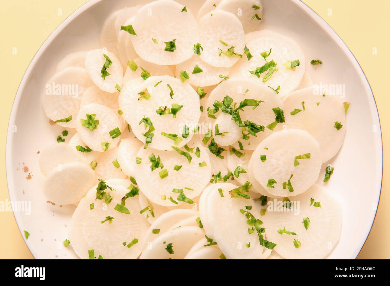 Bowl with slices of fresh daikon radish on yellow background Stock ...