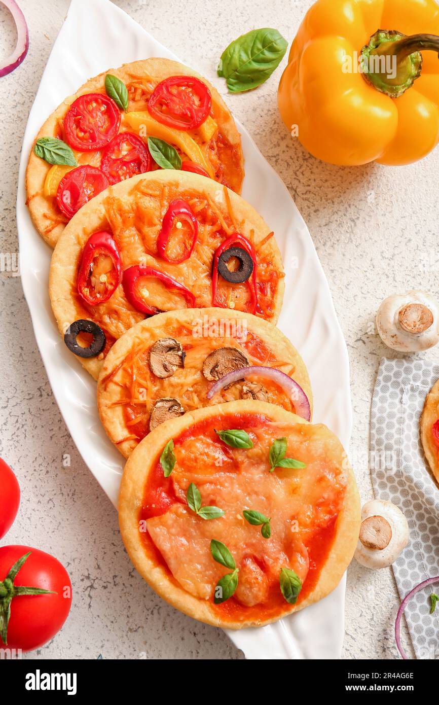 Plate with different tasty mini pizzas on white background Stock Photo ...