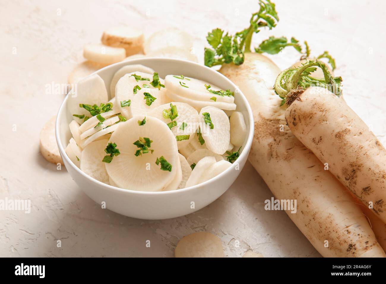 Bowl with slices of fresh daikon radish on white background Stock Photo ...