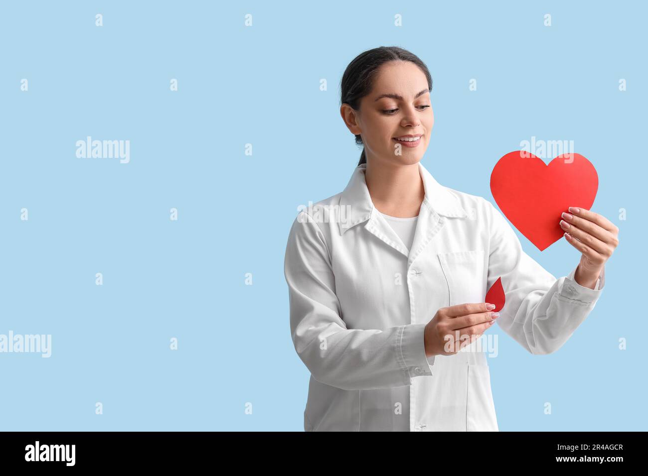 Female doctor with paper heart and blood drop on blue background Stock ...