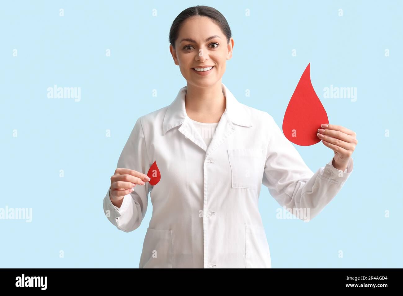 Female doctor with paper blood drops on blue background Stock Photo - Alamy