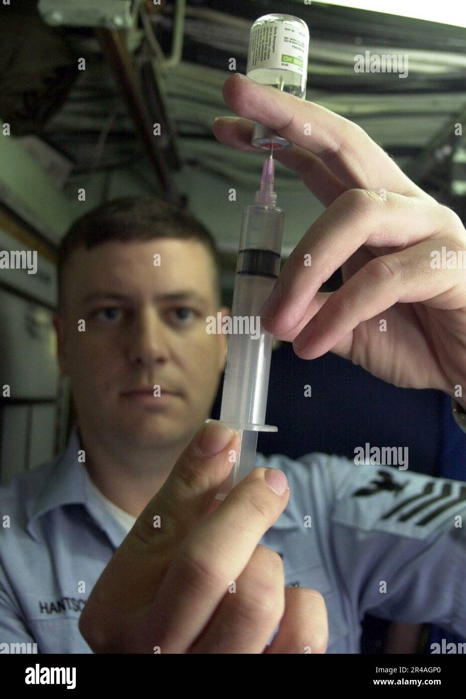 US Navy Hospital Corpsman 1st Class loads a syringe filled with flu ...