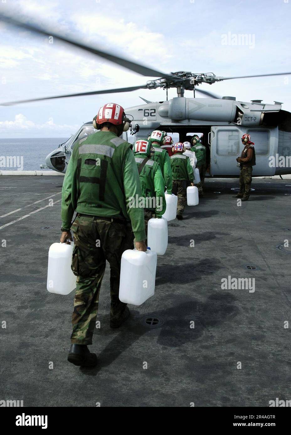 US Navy Sailor's aboard USS Abraham Lincoln (CVN 72) load jugs of ...